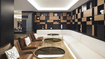 Uma área de lounge moderna com sofás de couro, mesas de centro de vidro e um design de parede quadriculado.