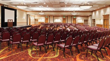 Sala de conferências com fileiras de cadeiras, palco e um púlpito.