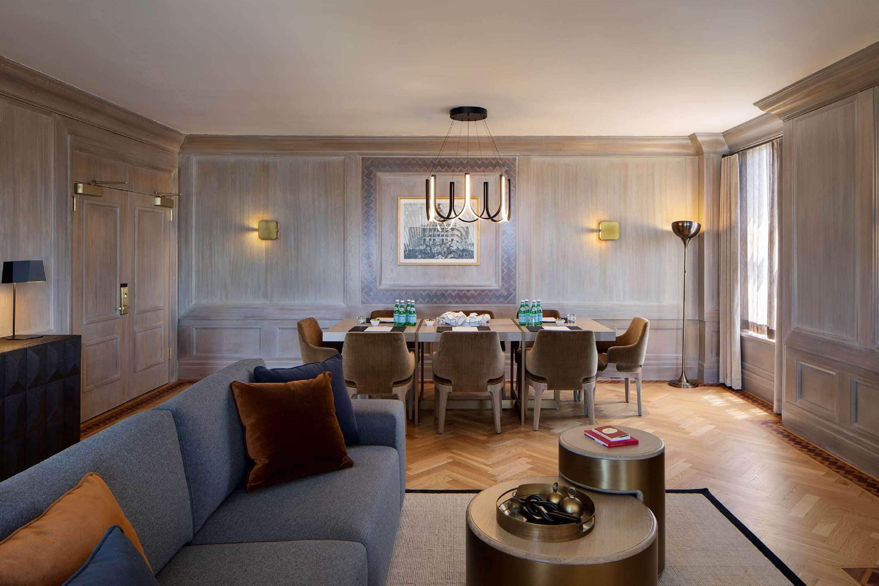Uma sala de estar ampla com um sofá moderno, uma mesa de jantar com cadeiras e um candelabro.