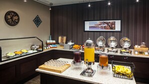 Disposição de buffet com diversos alimentos e um dispensador de suco.