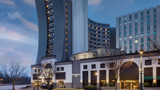 Um hotel moderno com fachada curva, vários andares e uma entrada destacada com um letreiro.