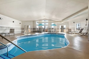 Piscina interna com vista clara, cadeiras de descanso e luminária central no teto.