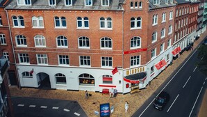 Um edifício de tijolos vermelhos com várias janelas e uma placa com a inscrição 'Milling Hotels'.