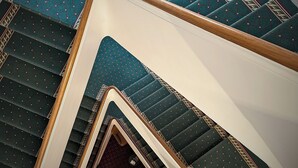 Escadaria em espiral com um padrão geométrico nos degraus e um corrimão de madeira.