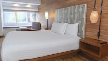 Quarto moderno com cama grande, cabeceira de madeira, mesas de cabeceira e janela com vista.