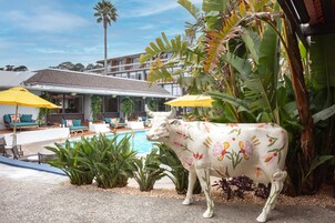 Uma estátua decorativa de vaca em um jardim com piscina e área de estar ao ar livre.