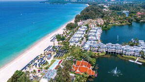 Vista aérea de um resort à beira-mar, com praia, marina e vários edifícios de hotel.