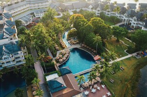 Um resort com uma piscina grande cercada por palmeiras e áreas de lazer.