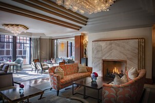 Um hall amplo com lareira, assentos confortáveis e um candelabro.