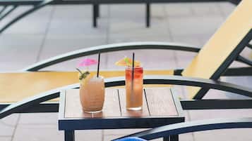 Uma fileira de espreguiçadeiras e uma mesa com duas bebidas.