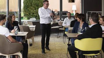 Restaurante com interior moderno, incluindo mesas e cadeiras arredondadas, e um garçom atendendo os clientes.