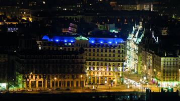 Uma paisagem urbana noturna com edifícios iluminados, incluindo um hotel notável com cúpula e iluminação azul.