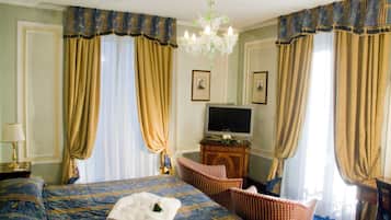 Quarto de hotel com uma cama grande, televisão, mesinha e uma cadeira.