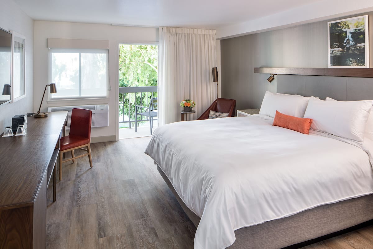 Quarto de hotel moderno com uma cama grande, uma escrivaninha e uma cadeira.