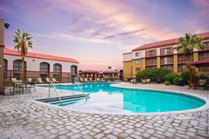 Área de piscina de hotel com espreguiçadeiras e piscina.