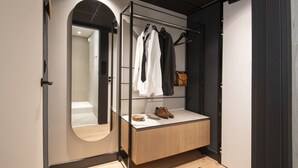 Um guarda-roupa moderno com espelho, cabides e um banco de madeira.