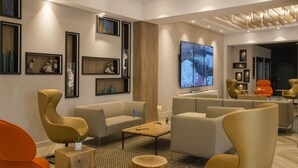 Um lobby moderno com sofás, uma mesa de centro e obras de arte penduradas na parede.