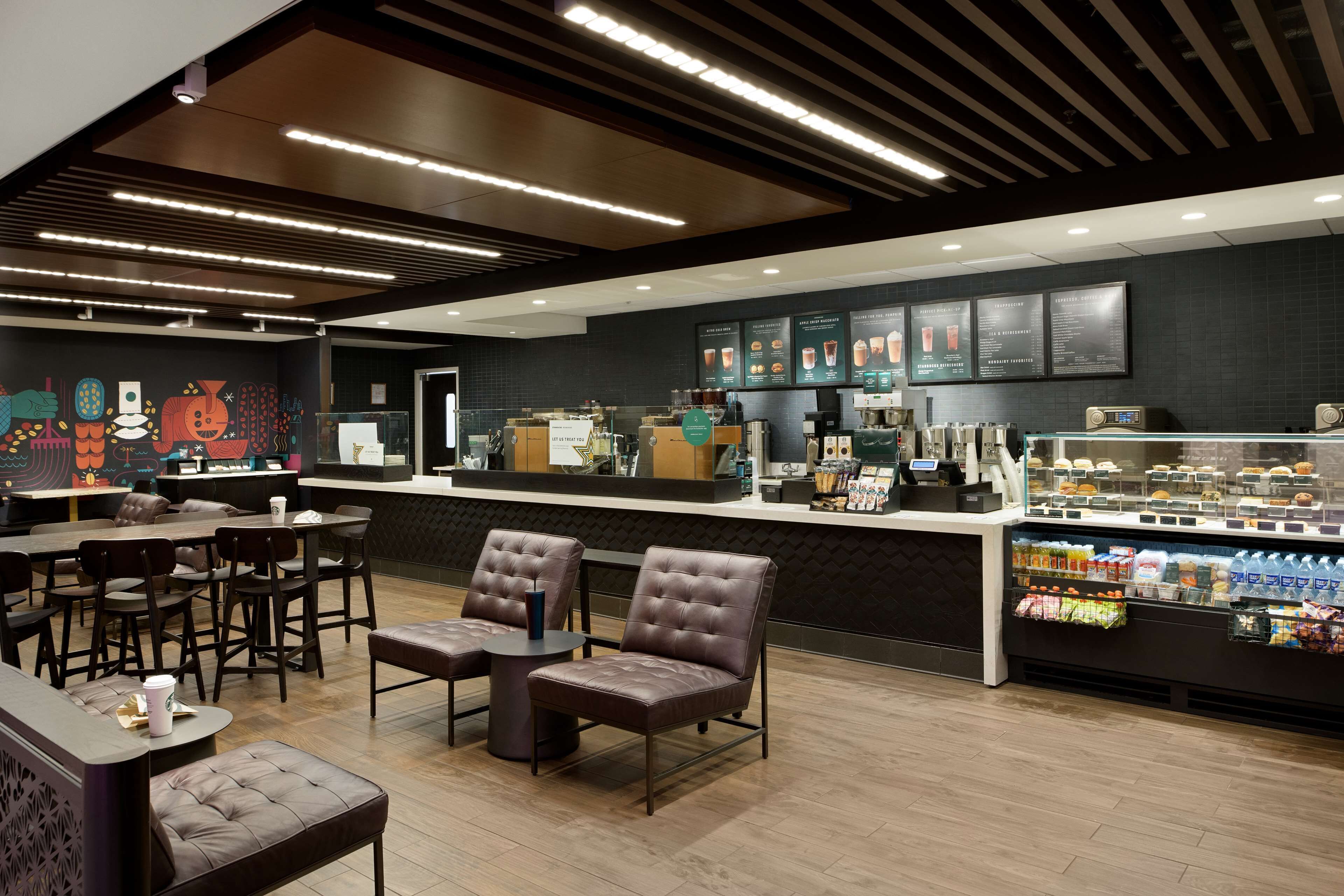 Um café moderno com assentos de couro, um balcão com máquina de café e uma vitrine com lanches.