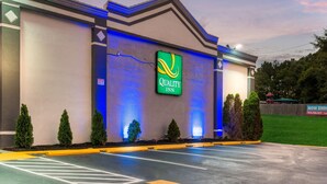 Um hotel Quality Inn com uma placa de destaque, estacionamento e área ajardinada com arbustos bem cuidados.