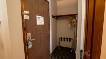 Quarto de hotel com porta de madeira, porta-toalhas e cortina de chuveiro.