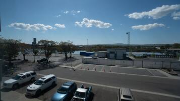 Um estacionamento com vários veículos, incluindo SUVs e uma caminhão, e um edifício com telhado azul ao fundo.