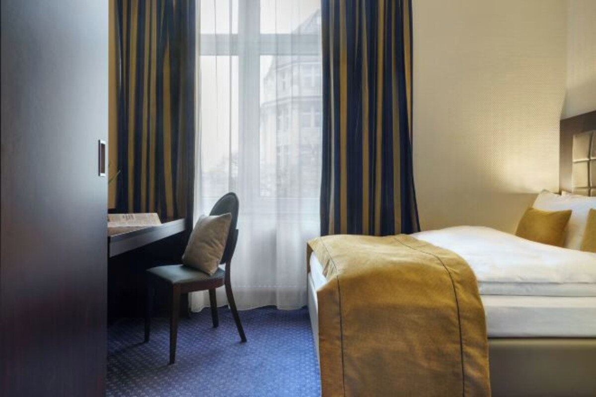 Quarto de hotel com cama, escrivaninha e cadeira.