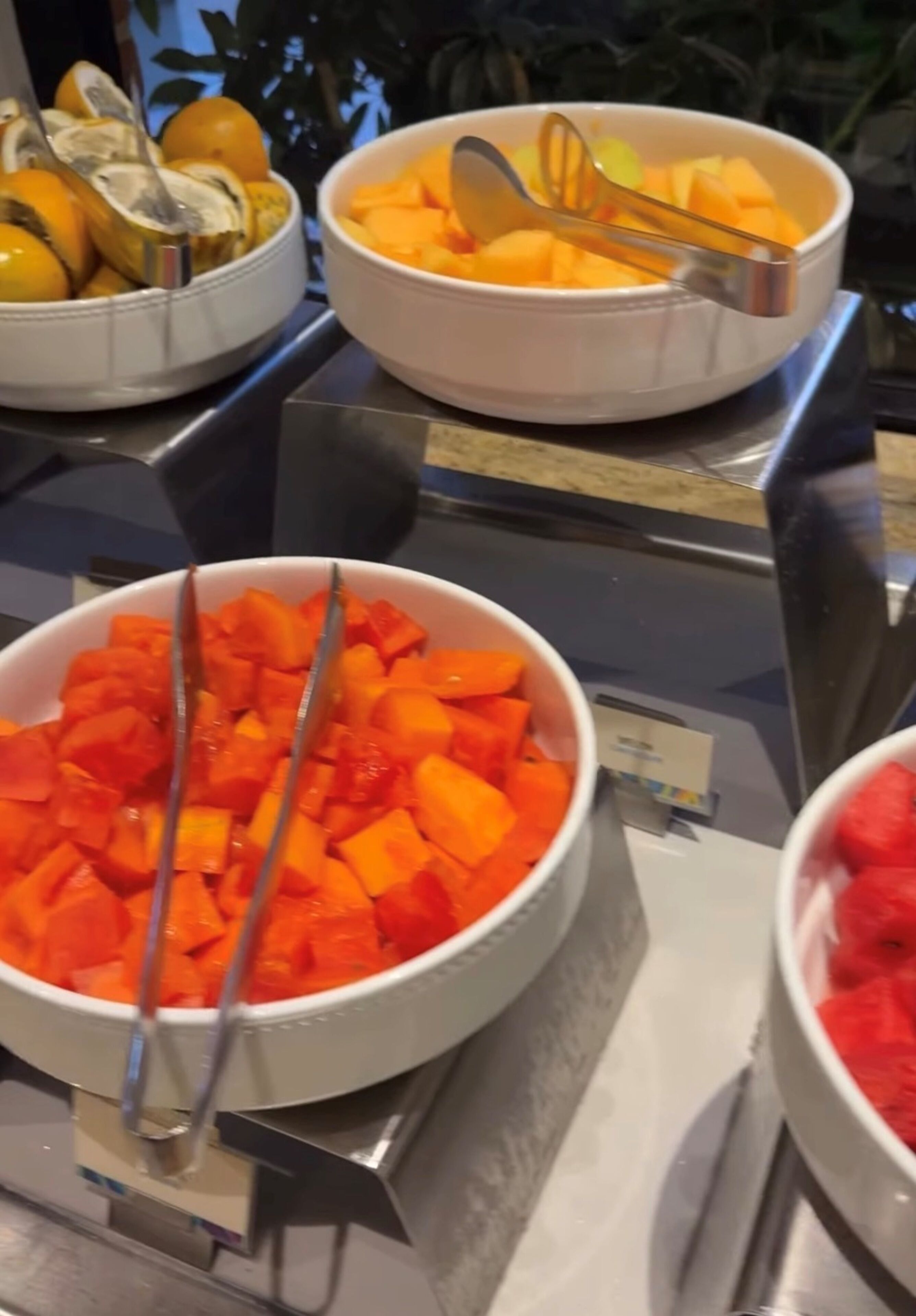 Buffet com diversas opções de frutas em recipientes.