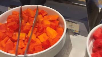 Buffet com diversas opções de frutas em recipientes.