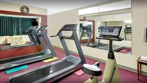 Ginásio de hotel com esteiras, bicicleta ergométrica e um espelho grande.