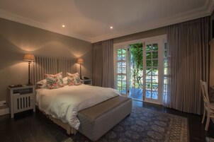 Um quarto espaçoso com uma cama grande, duas luminárias de cabeceira, uma mesa de cabeceira e vista para o exterior por uma porta de correr.