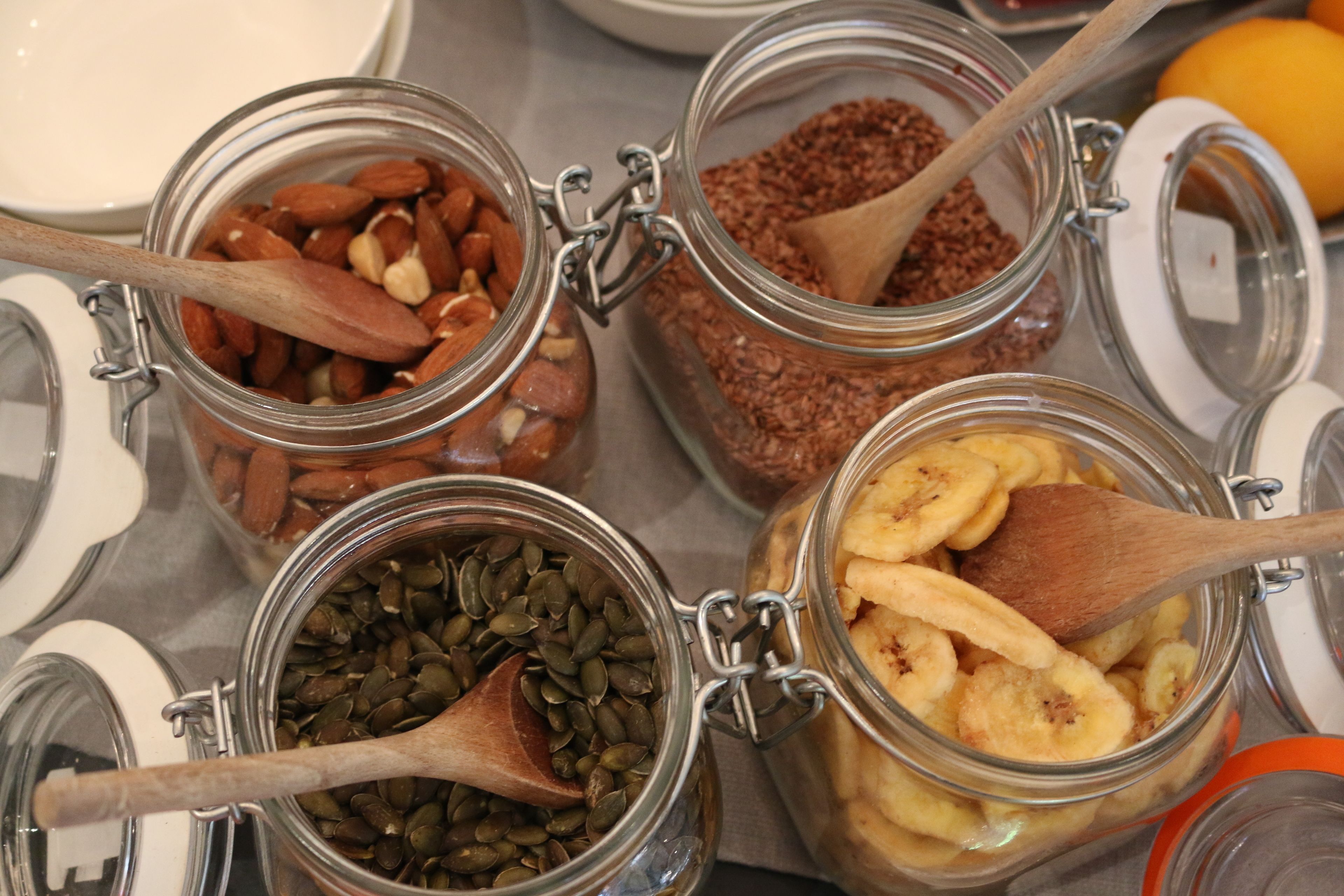 Uma mesa com vários potes contendo nozes, sementes e frutas secas.