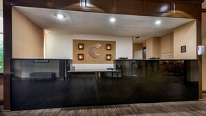 Uma área de recepção moderna com um balcão preto, uma parede de madeira com design em forma de crescente lunar e quatro luminárias fixadas na parede.