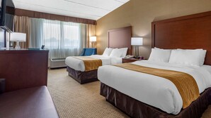 Quarto de hotel com duas camas, uma escrivaninha, uma cadeira e uma televisão.