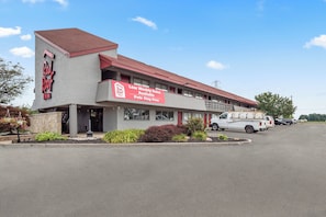 Um motel com telhado vermelho e um letreiro anunciando tarifas semanais acessíveis e hospedagem gratuita para animais de estimação.