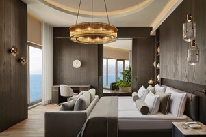 Quarto moderno com cama grande, escrivaninha e vista para o mar.