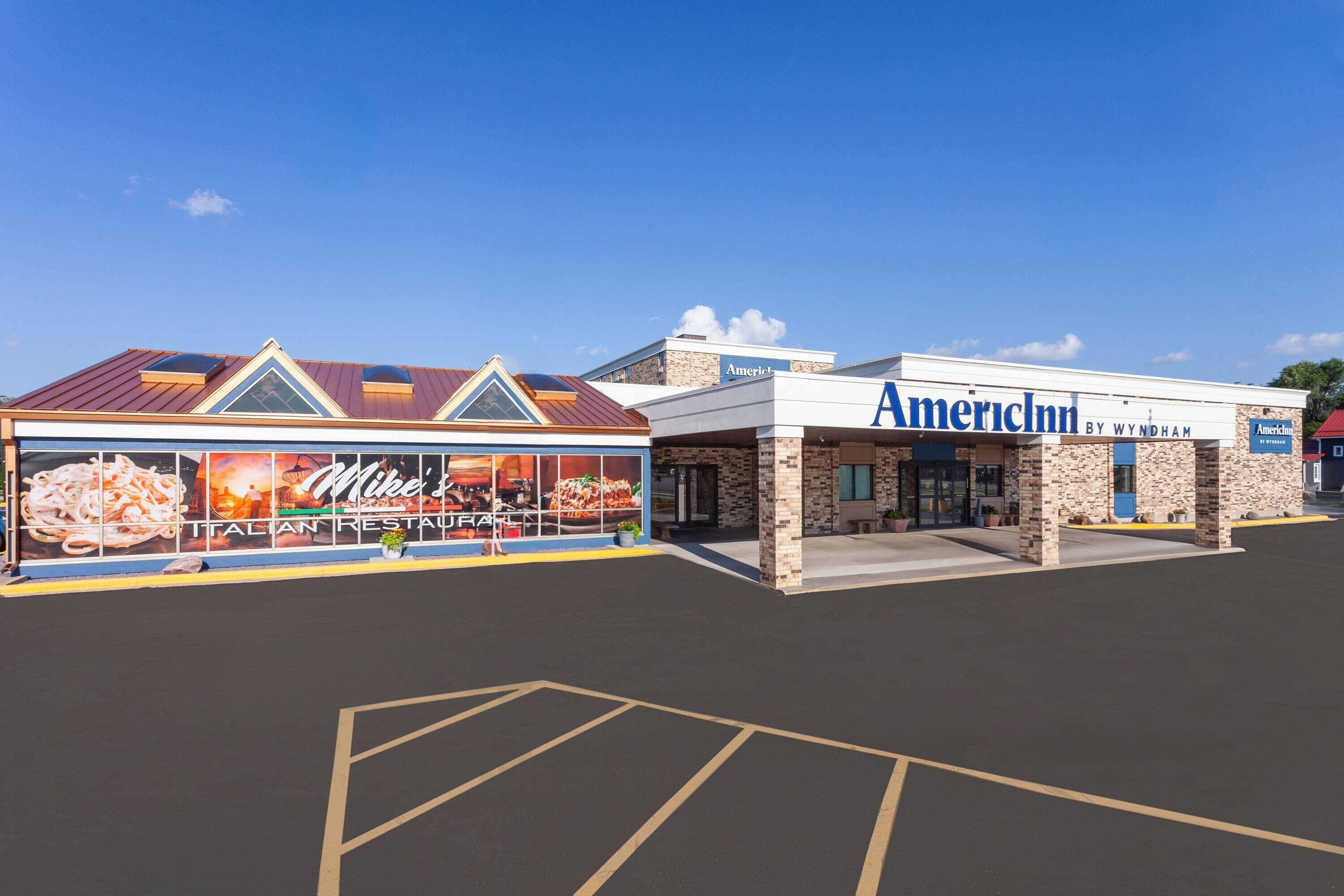 Um edifício comercial com a placa American Inn, um restaurante com grande vitrine e um estacionamento.