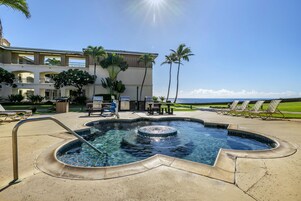 Área de piscina com hidromassagem, espreguiçadeiras e vista para o oceano.