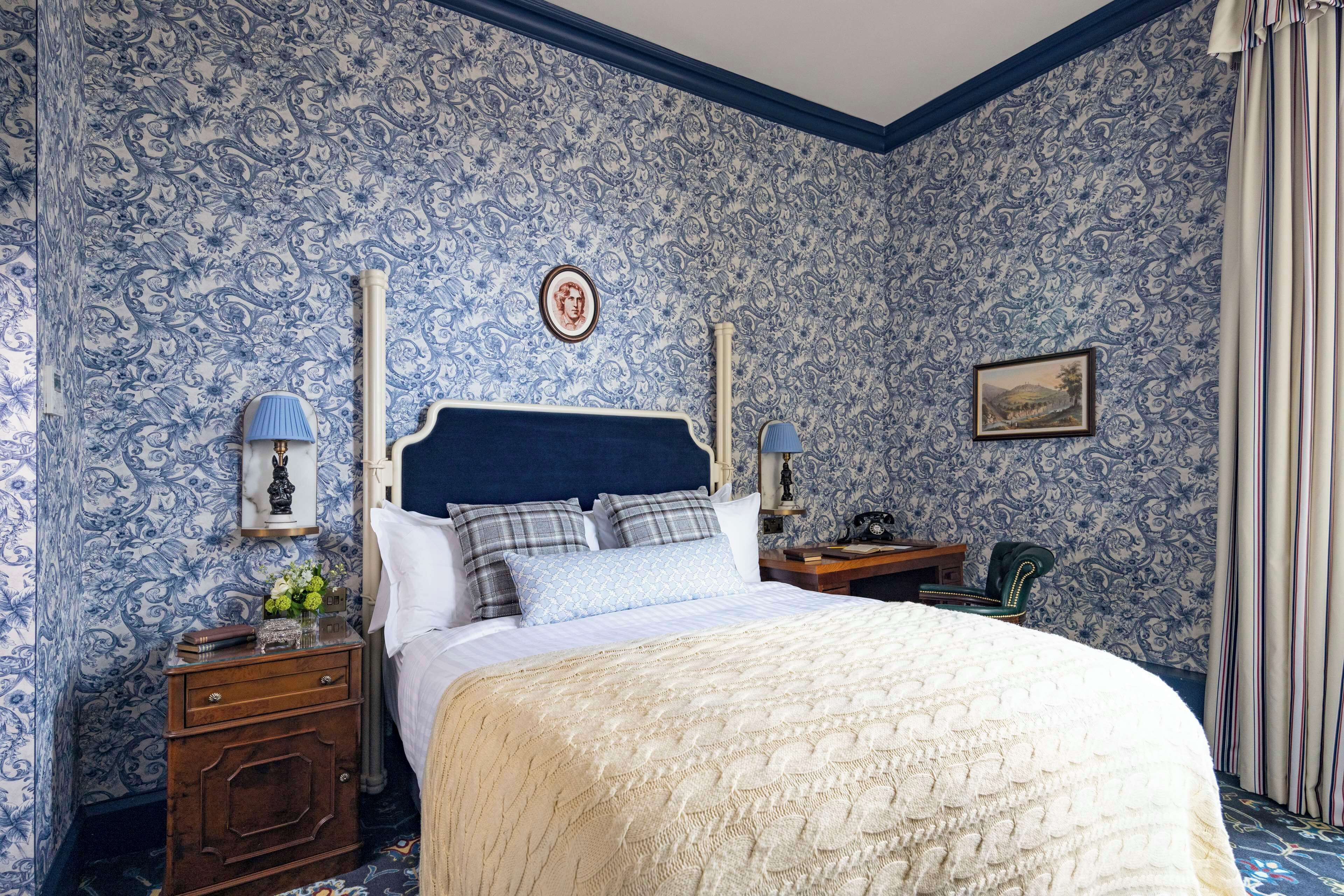 Quarto com uma cama grande, duas mesas de cabeceira, um criado-mudo, um quadro na parede e uma janela com cortinas.