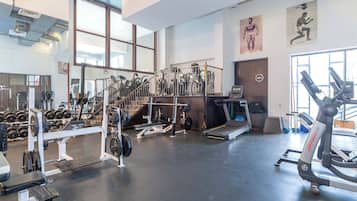 Uma academia com diversos equipamentos de exercício, incluindo esteiras, aparelhos de musculação e halteres.