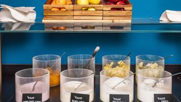 Buffet com diversas opções de frutas e recipientes de iogurte identificados.