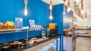 Uma área de buffet com diversos tipos de comida, um espaço para sucos e um aviso indicando opções sem glúten.