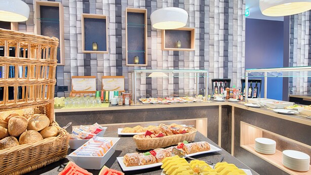 Buffet com diversos alimentos e cestas de pão.