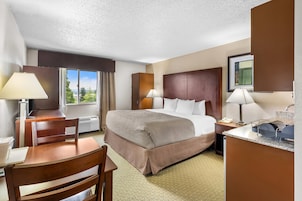 Quarto de hotel com cama, escrivaninha, cadeira e vista para o exterior.