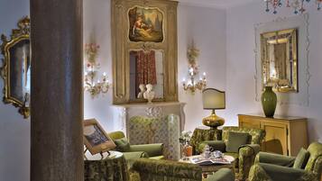Um quarto com móveis estofados verdes, lareira e um candelabro.