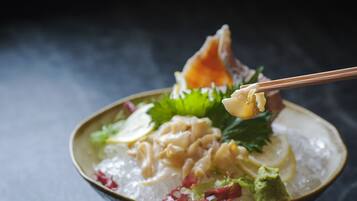 Uma tigela de ramen com vários acompanhamentos e um pedaço de peixe sendo segurado por pauzinhos.