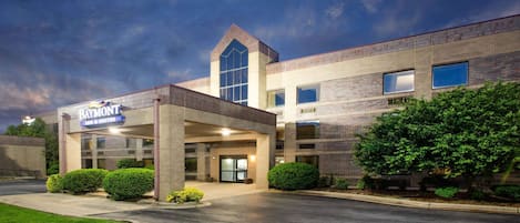 Hotel com design moderno, destacando uma entrada imponente, área coberta e fachada de tijolos.