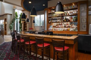 Uma área de bar com balcão, banquetes e diversas garrafas.