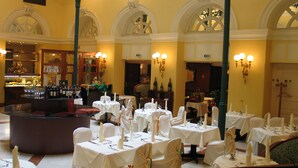 Restaurante com mesas redondas preparadas para refeições, com toalhas brancas e velas.