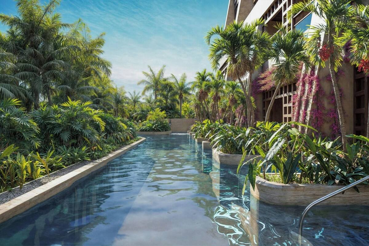 Piscina cercada por plantas tropicais e um edifício com varandas.