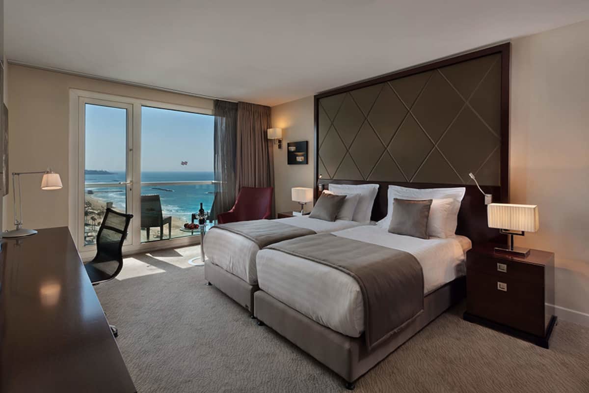 Quarto de hotel com uma cama grande, uma escrivaninha e vista para o oceano.